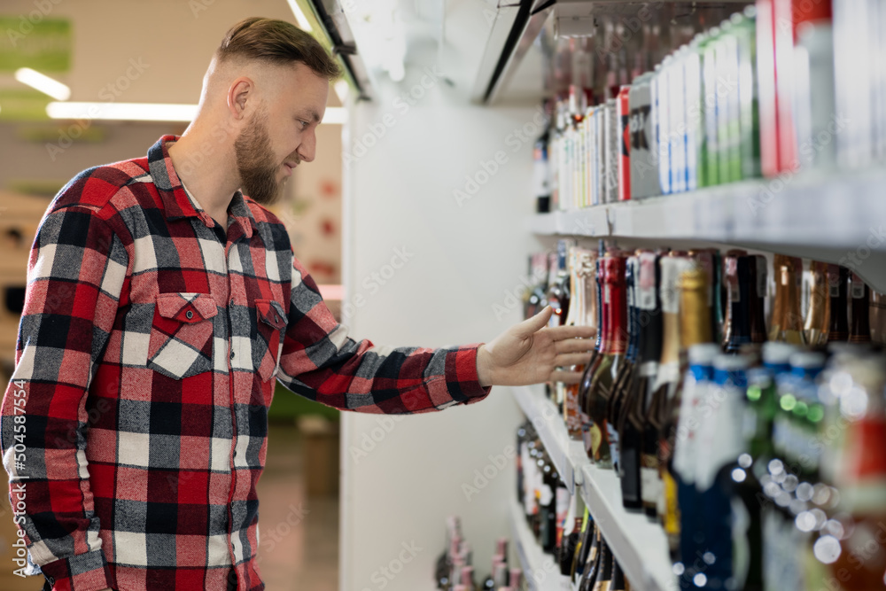 handsome male shopper choosing champagne in supermarket, guy standing ...