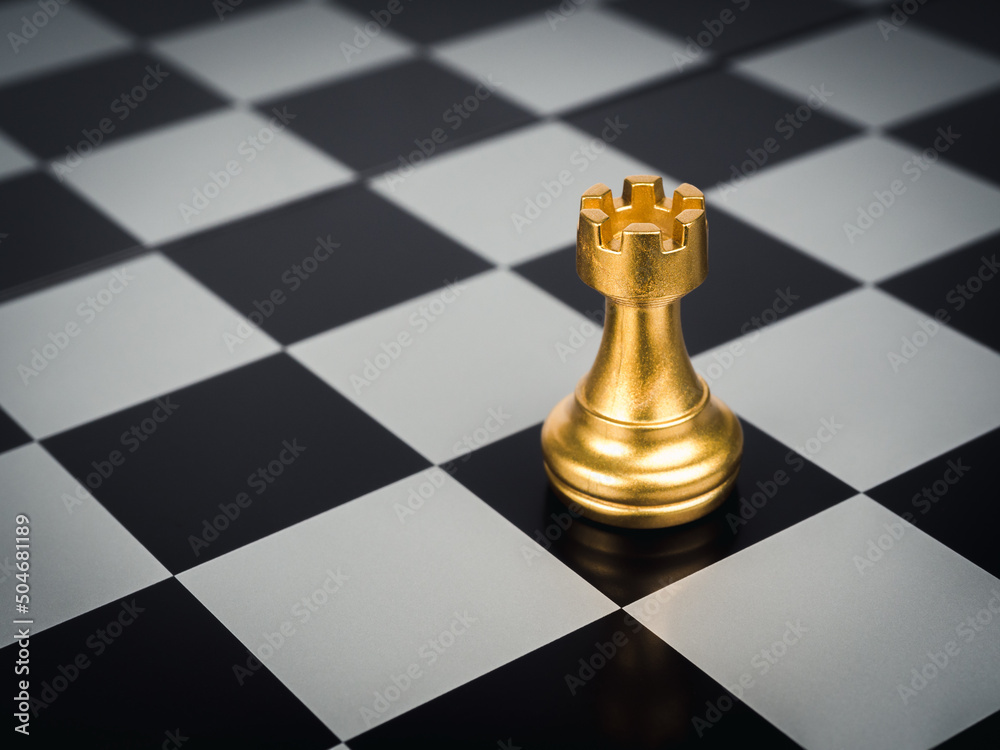 The golden rook chess piece standing alone on chess board background ...