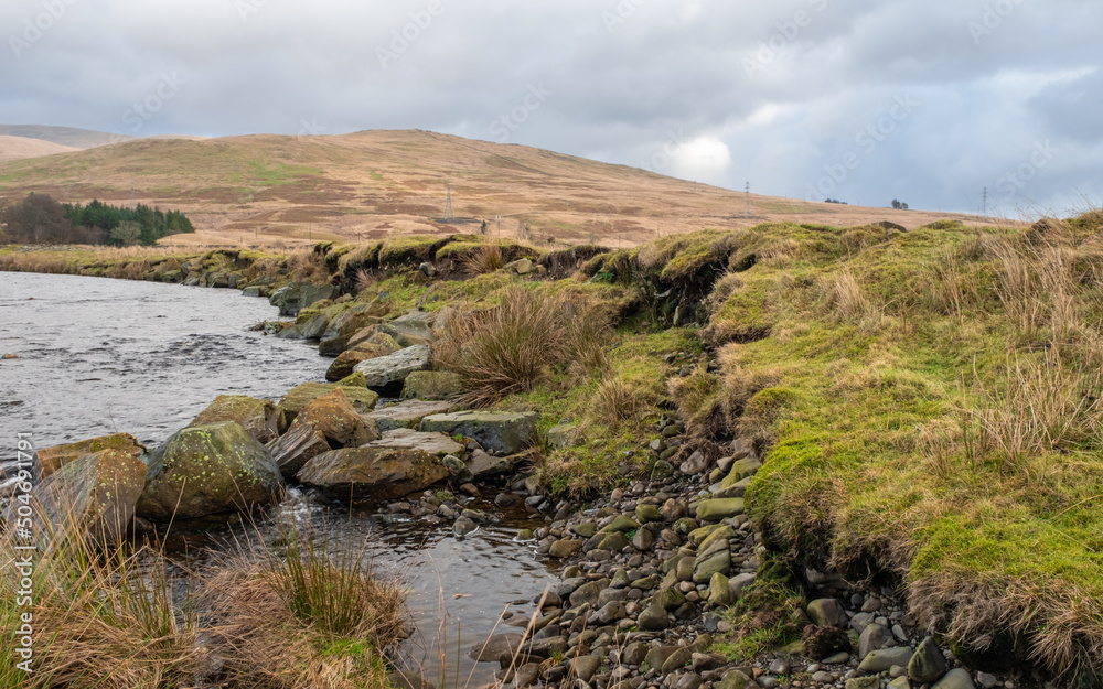 Failed river erosion protection with rip-rap rocks washed out of a ...