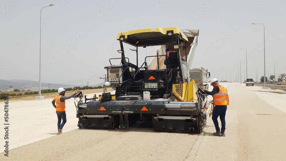 workers on the road, laying and compacting the layer before laying ...