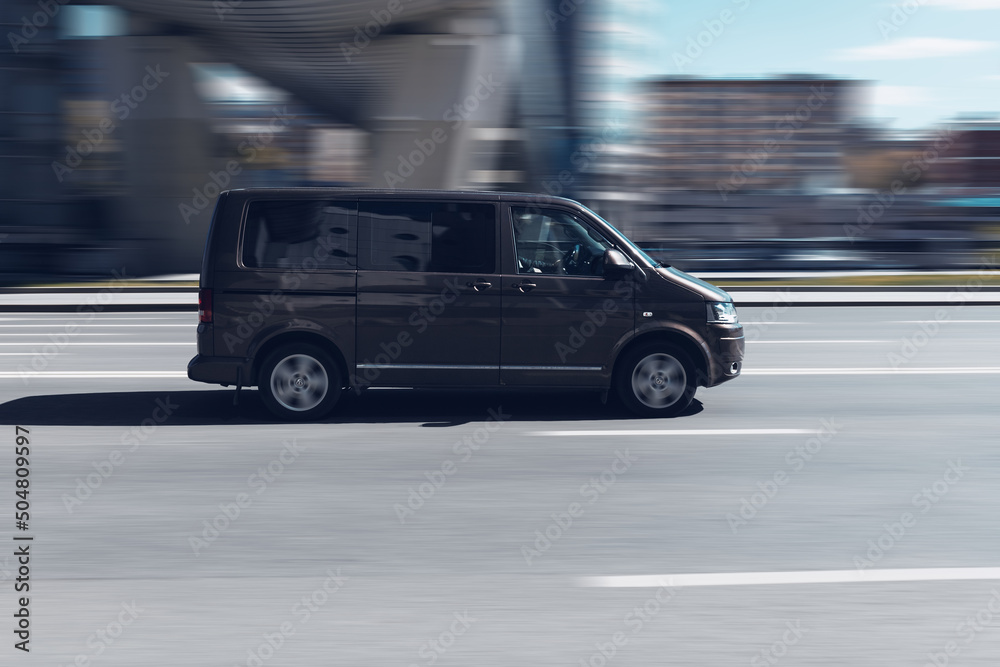 Fast moving Volkswagen Multivan T5 on the city road. Brown van is ...