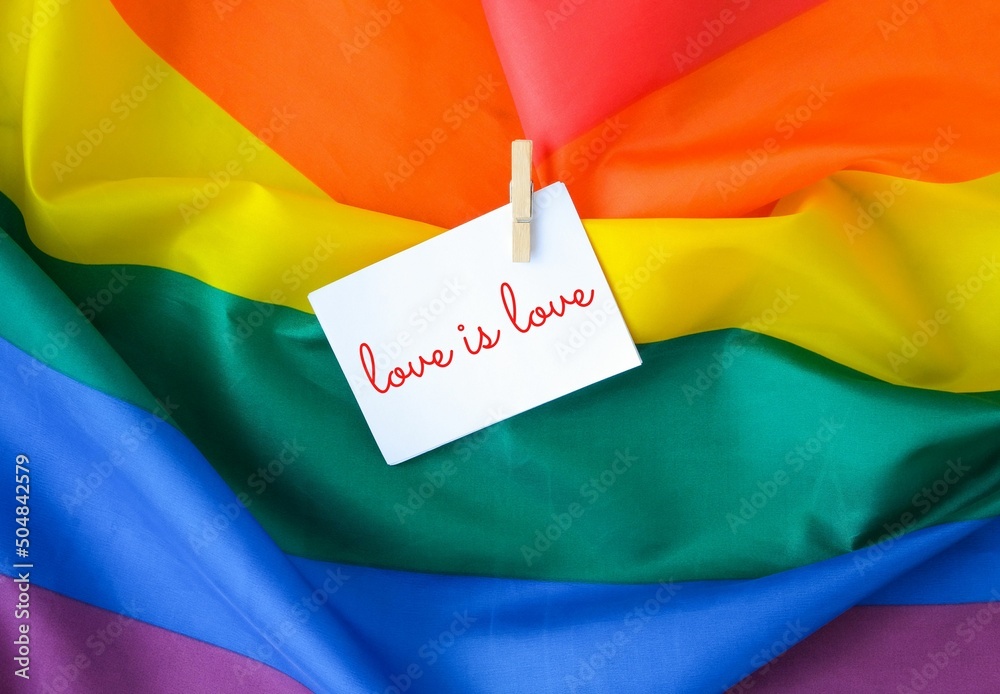 Rainbow flag with text LOVE IS LOVE message on paper note. Rainbow ...