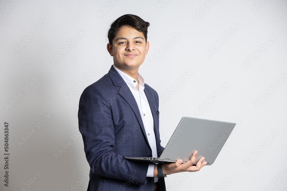 Young smiling Indian teenager boy wearing formal outfit holding laptop ...