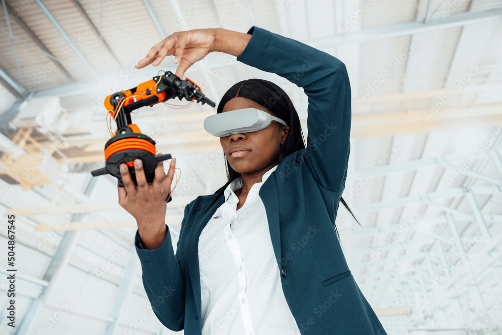 Engineer wearing virtual reality simulator holding model of robotic arm ...
