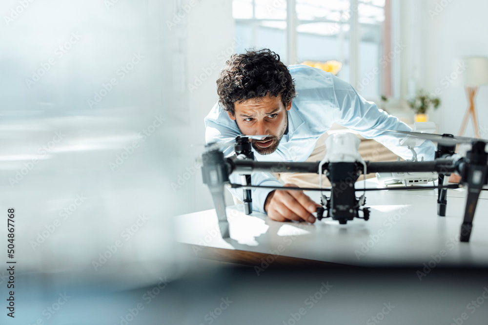 Businessman analyzing drone at desk in office Stock Photo | Adobe Stock