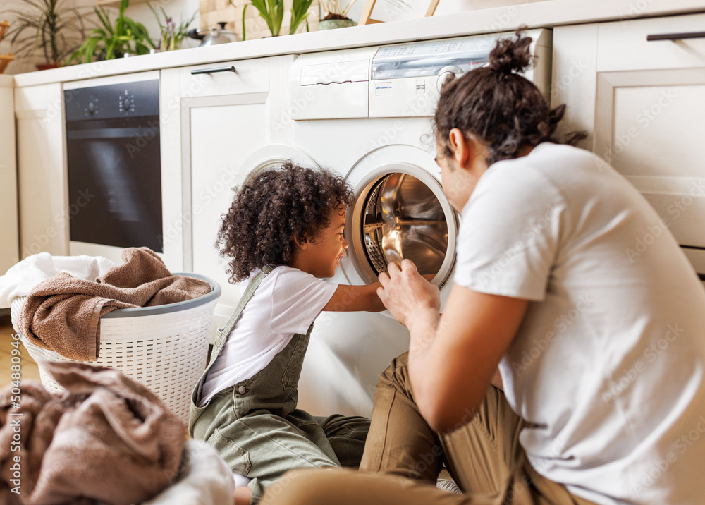 Son helping dad to load washing machine Stock Photo | Adobe Stock