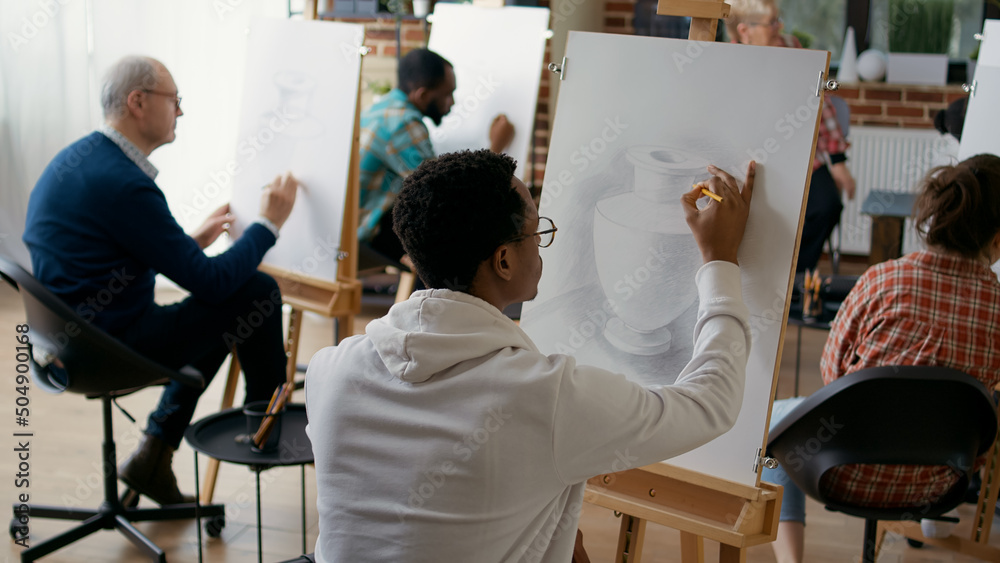 African american student using pencil to draw vase model on canvas in ...