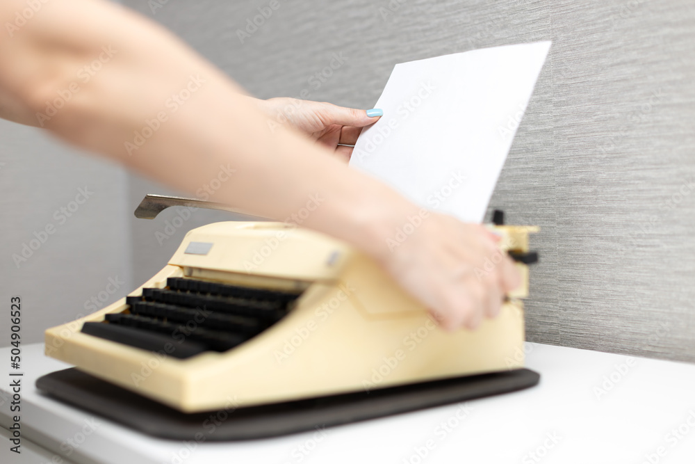 woman filling paper into an old typewriter Stock Photo | Adobe Stock