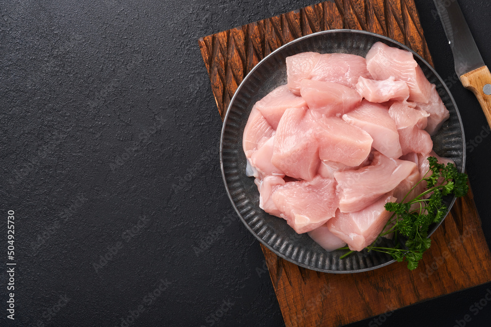 Raw chicken breast sliced or cut pieces on wooden cutting board with ...
