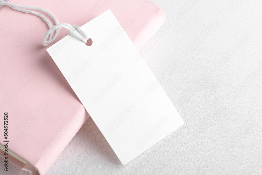 Rectangle white gift tag mockup with white cord, close up on pink book ...