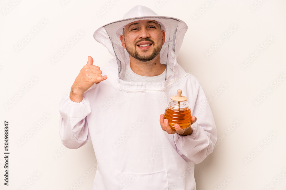 Hispanic beekeeper man holding honey isolated on white background ...