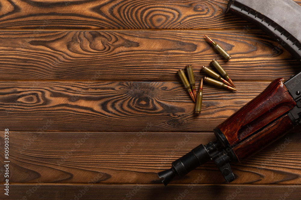 Bullets and ammo magazine with Kalashnikov assault rifle on brown wood ...