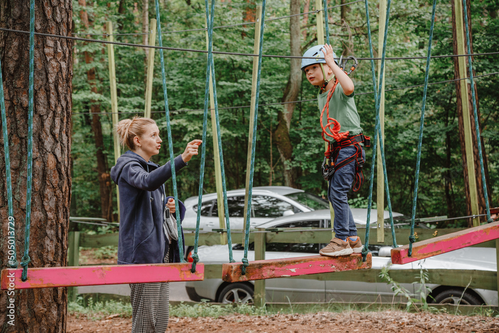 Brave little boy having fun at adventure park and smiling to camera ...