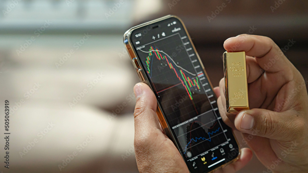 Hand holding mobile and gold bar, In mobile, there is a candlestick ...