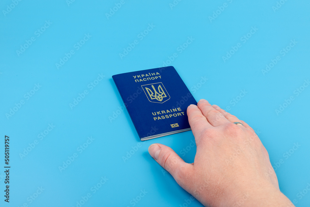 Passport of a citizen of Ukraine in a female hand on a blue background ...