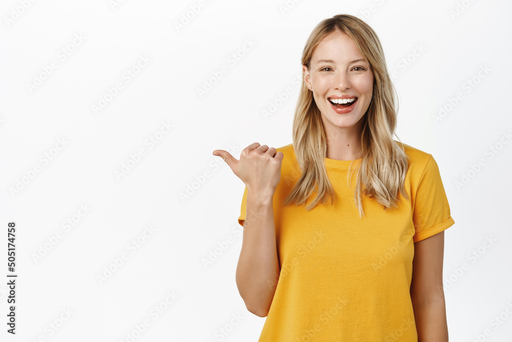 Portrait of happy smiling cute girl, woman pointing finger left at copy ...