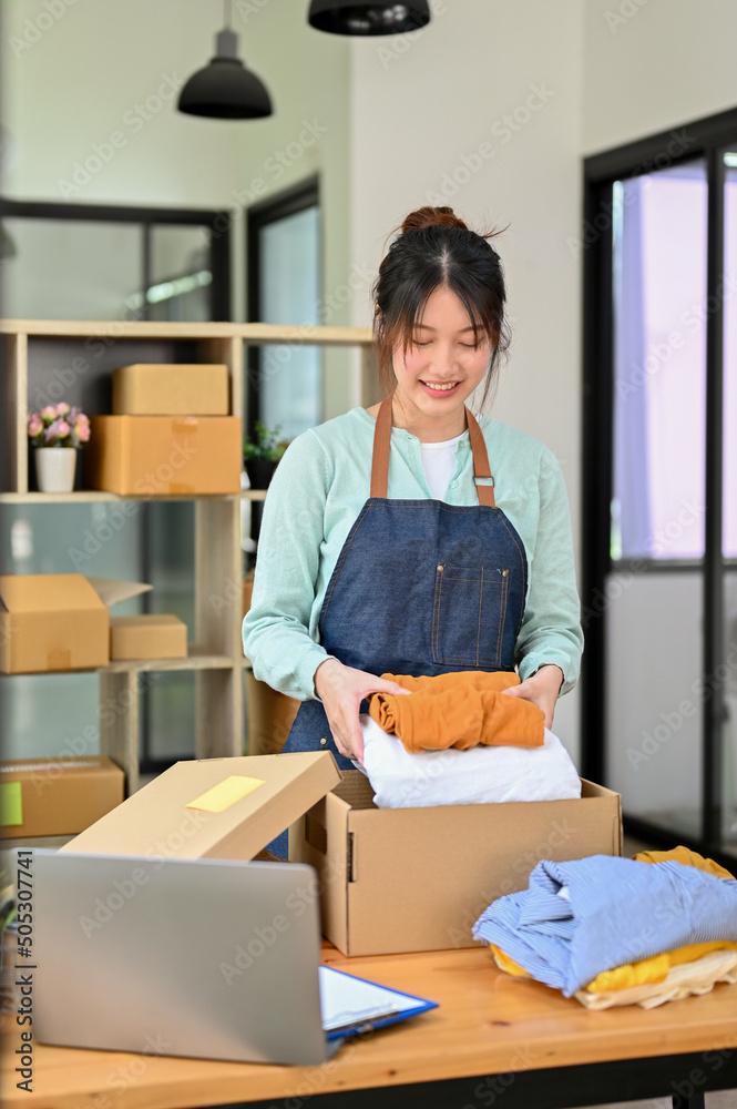 Small Business Startup, Female clothes shop owner packing goods in a ...