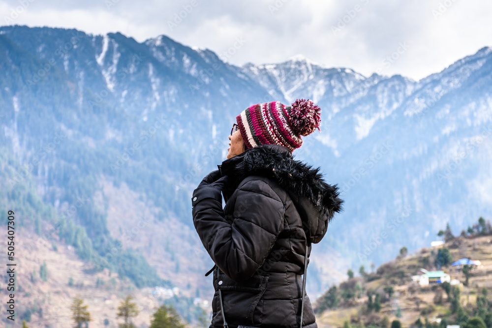 Young woman traveller looking towards the Himalayas mountains in Sainj ...