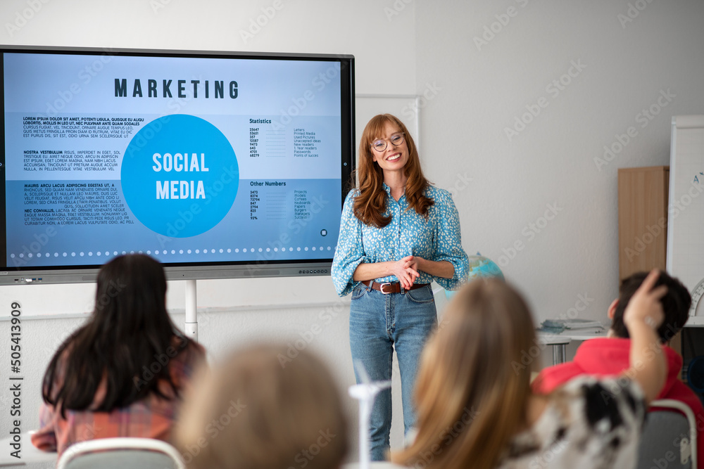 Young High school teacher giving marketing lesson to students in ...