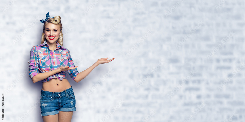 Foto Stock Pinup woman holding, showing or giving. Happy smiling girl ...