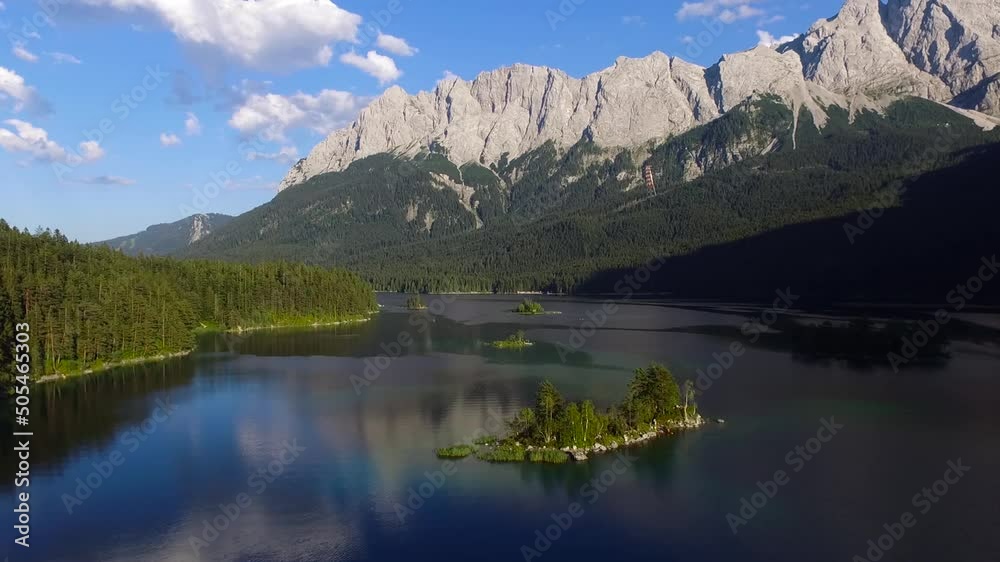 Aerial footage of mountain lake Eibsee beneath Zugspitze peak with ...