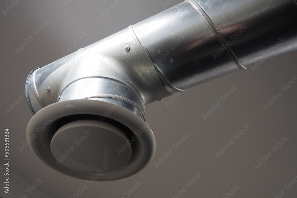 Extractor hood in a public toilet. Round metal pipe with gray air ...