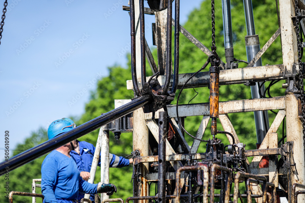 Oil and gas industry worker operates oil rig drill pipes on an oil well ...