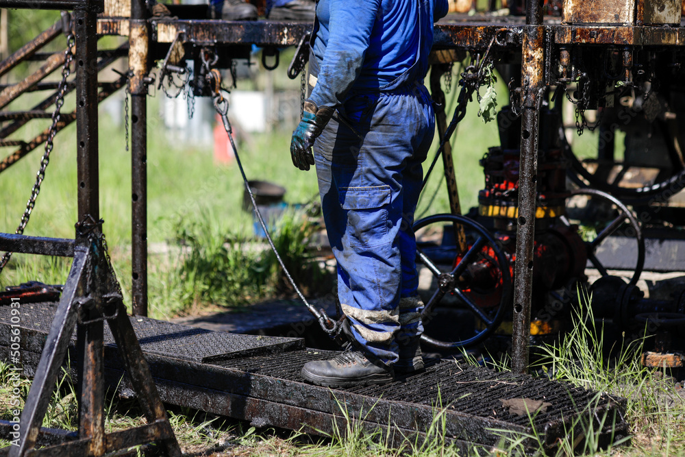 Oil and gas industry worker operates oil rig drill pipes on an oil well ...