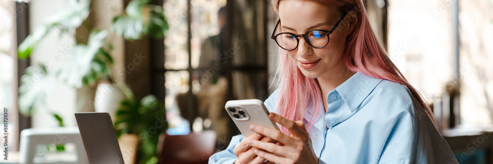 Young woman using laptop and cellphone while sitting in cafe Stock ...