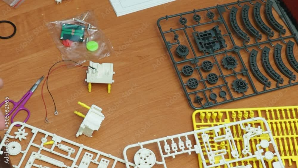 young male constructor scientist assemble the wheeled machine robot in ...