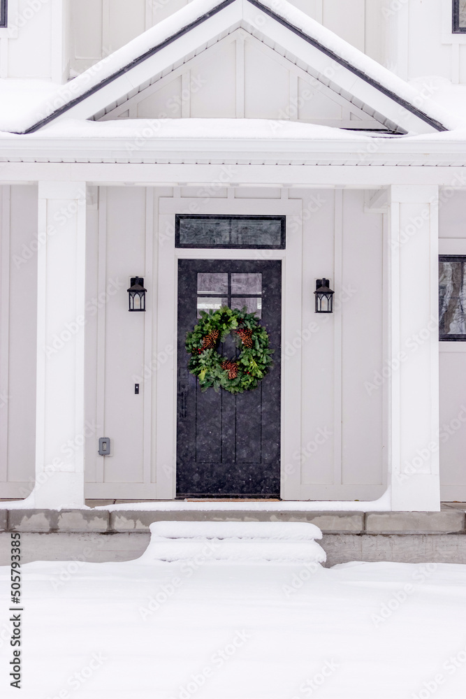 A modern farmhouse front porch, covered in a fresh layer of winter snow ...