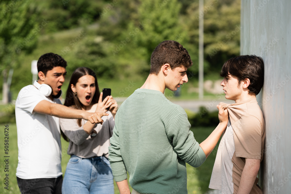 Teenager bully menacing boy while friends are recording. Bullying and ...