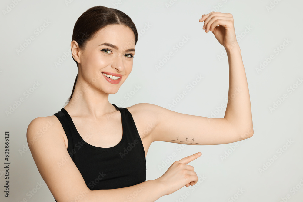 Slim young woman with marks on arm against light background. Weight ...