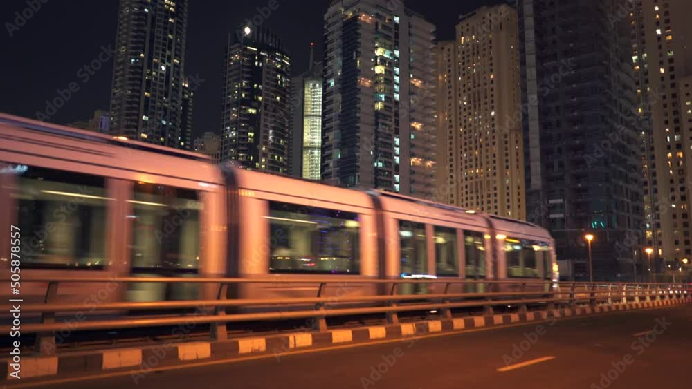 Static shot of Dubai Metro Train passing with Dubai skyline buildings ...