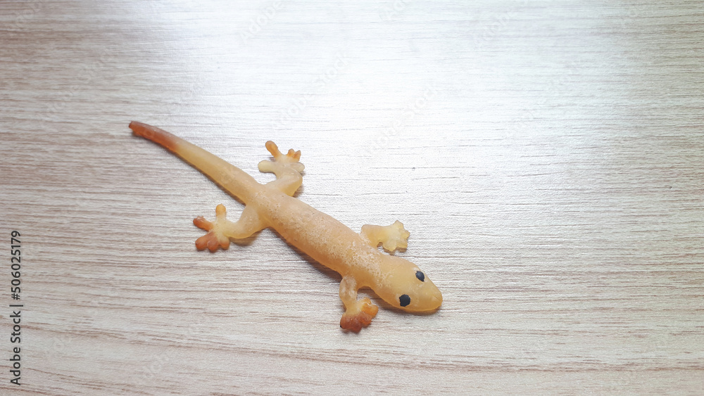 Fake rubber lizard toy on white wall. Fake lizard which is made of ...