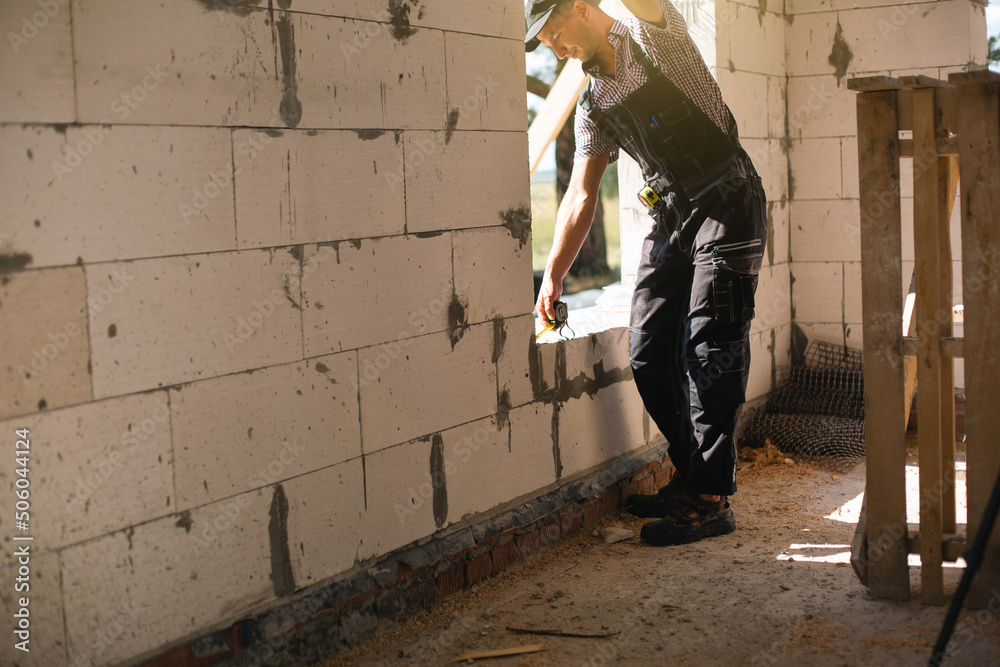 Construction worker at construction site measures the length of window ...