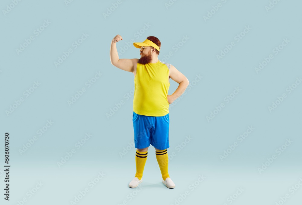 Fat guy demonstrating his muscles. Chubby young man in yellow and blue ...