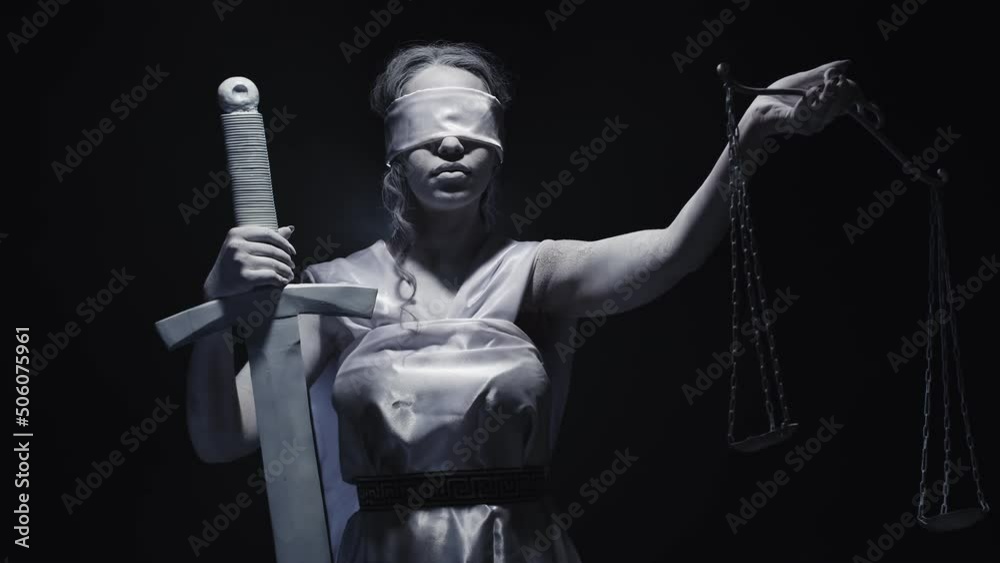 Woman dressed and makeup as goddess justice holds sword and lifts scale ...