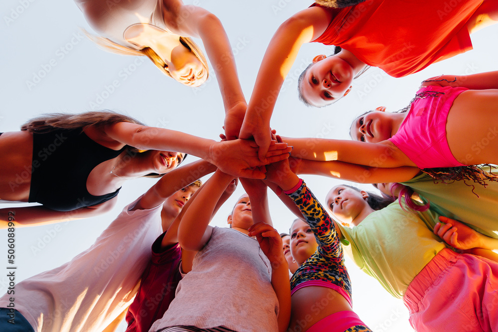 A large group of children, boys and girls, stand together in a circle ...