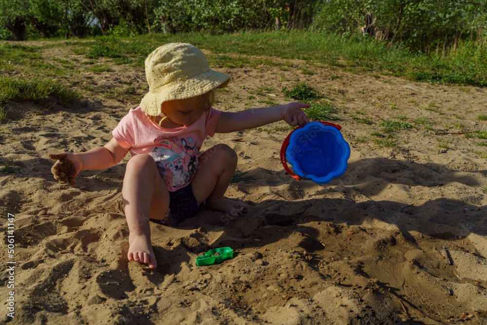 little baby playing with a blue plastic bucket filled with water on a ...