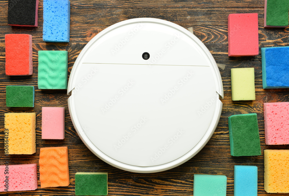 Robot vacuum cleaner and different sponges on wooden background Stock ...
