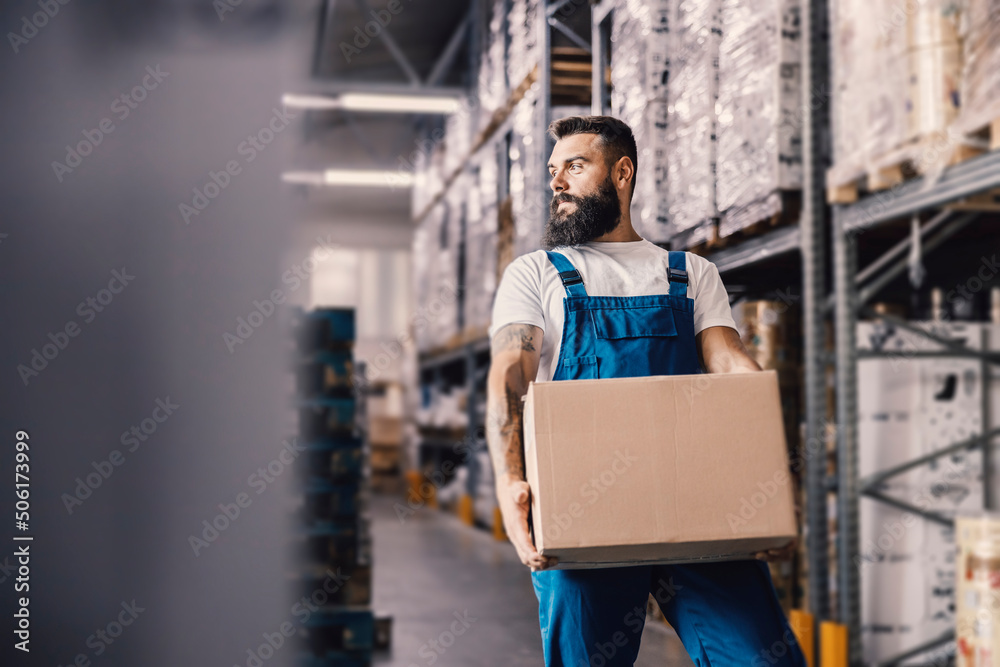 A warehouse worker carrying heavy box and relocating it. Stock-Foto ...