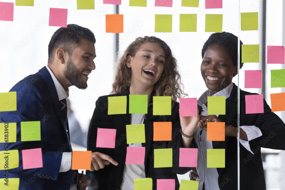 Three overjoyed multi racial friendly colleagues work together in ...