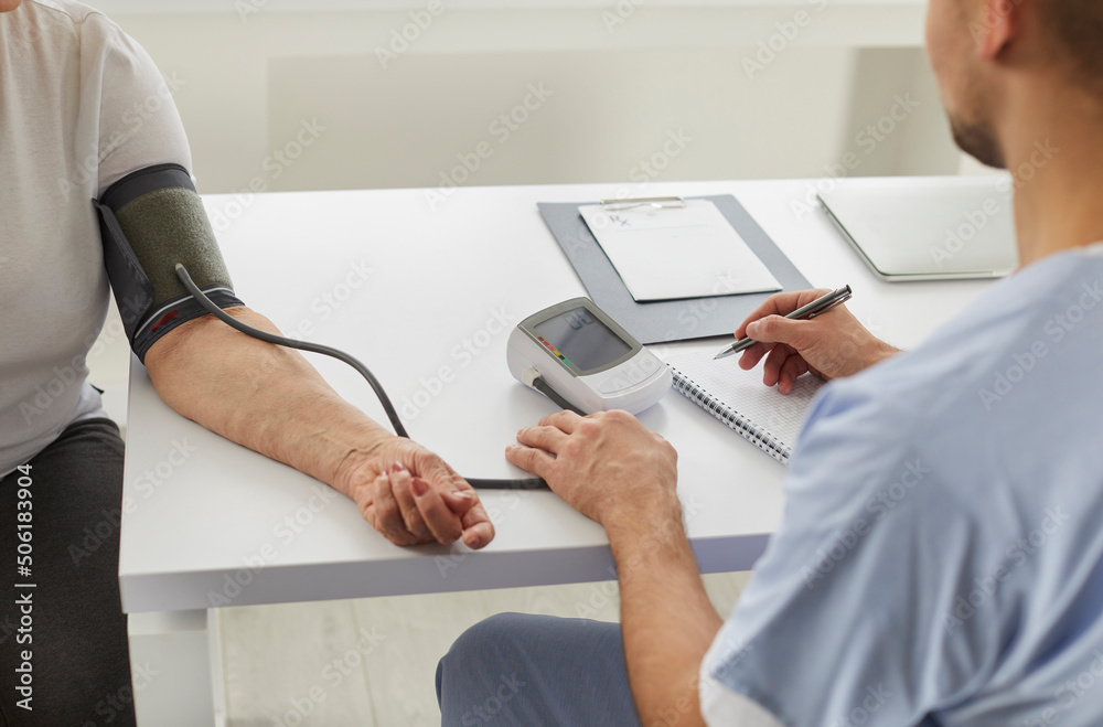 Doctor at clinic checking arterial pressure of older woman. Senior lady ...