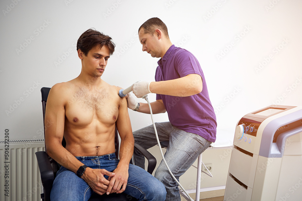 Shock wave therapy of the shoulder joint. Physiotherapist doctor uses ...