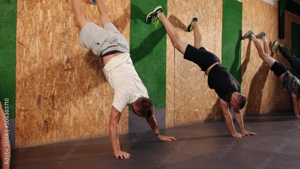 Athlete walks on hands while standing upside down near wall. Full body ...