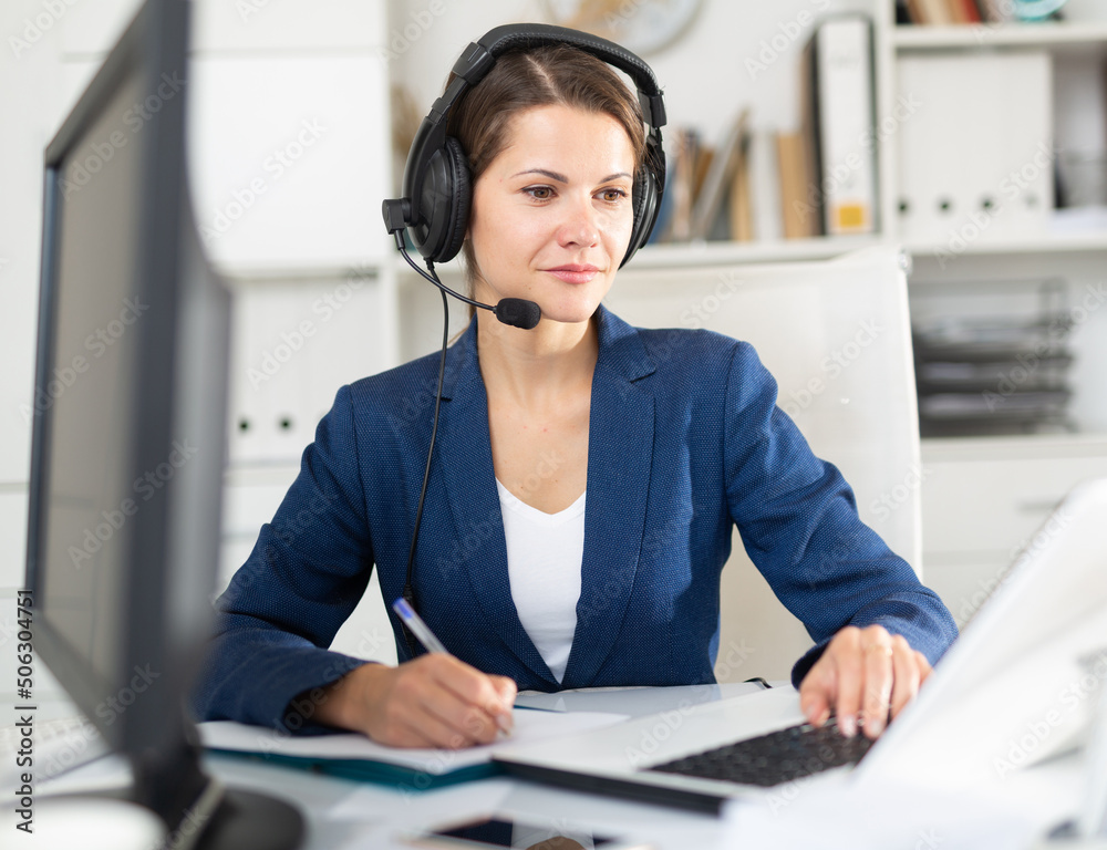 Smiling young female operator talking with customer using headset at ...