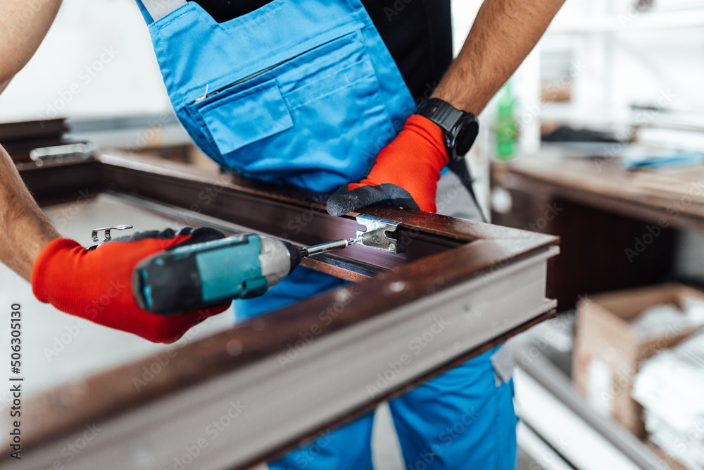 Manual worker works in a carpentry factory, he is assembling PVC ...