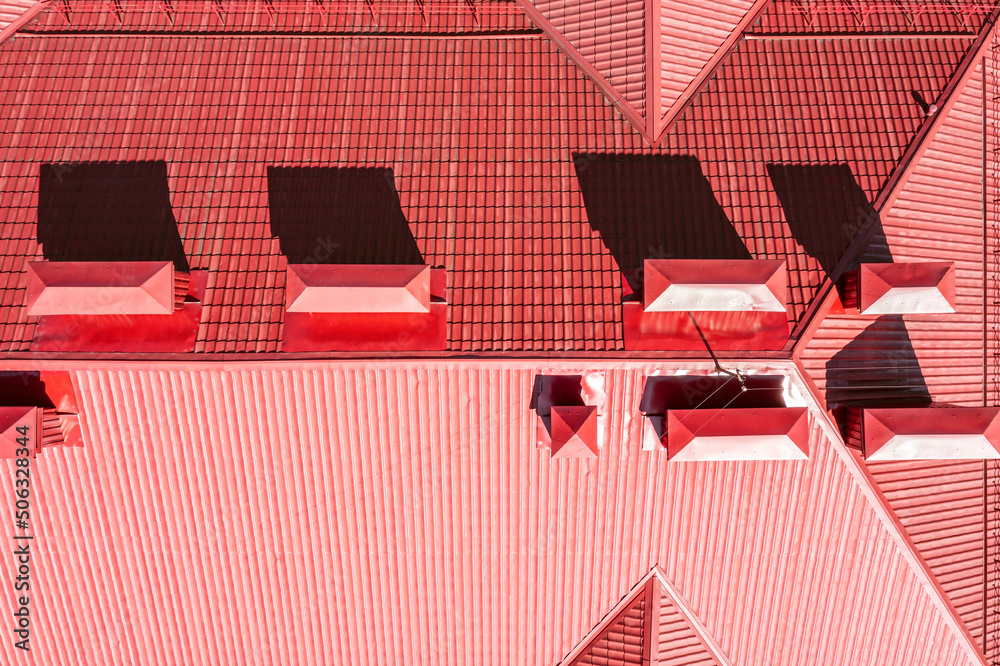 red corrugated metal sloping roof with chimneys and ventilation pipes ...