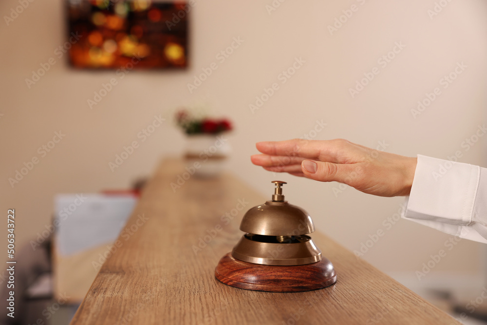 Woman ringing hotel service bell at wooden reception desk, closeup ...
